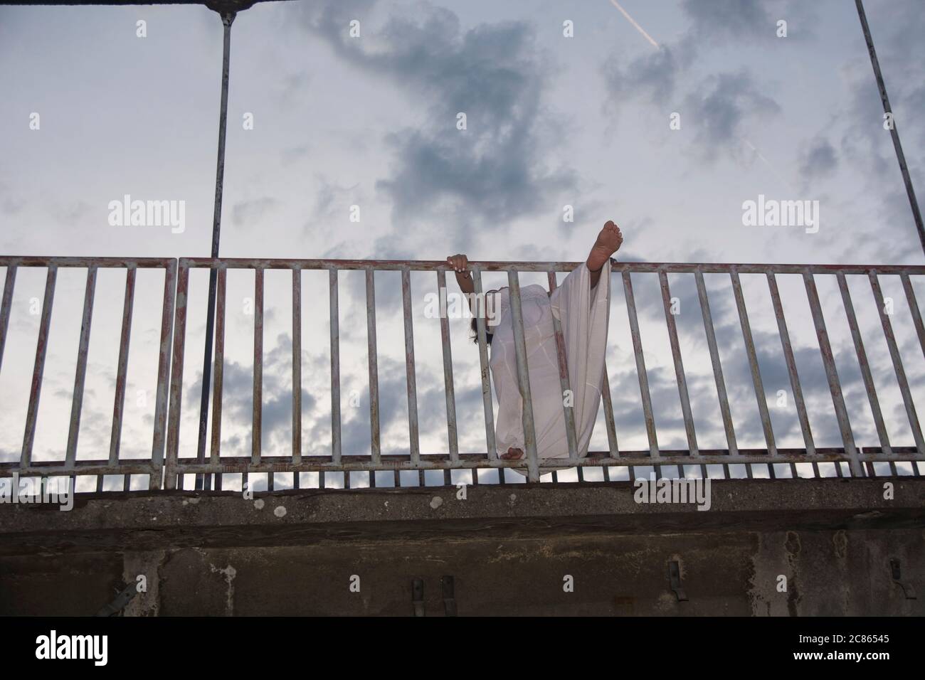 An attractive female model poses on a fence from the footpath of a ...