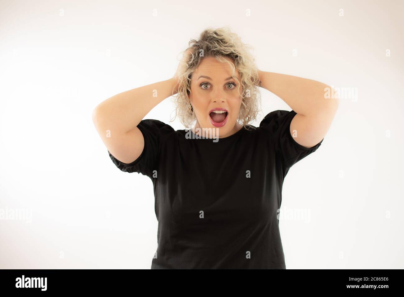 Blonde young woman smiling making surprise gesture Stock Photo - Alamy