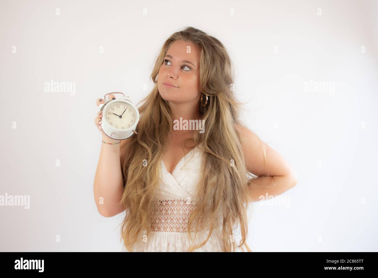 Blonde girl in white dress showing a clock Stock Photo - Alamy