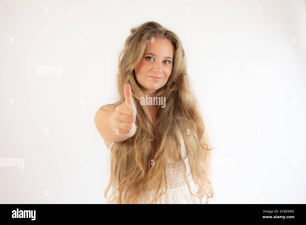 Girl in white dress making finger up gesture Stock Photo - Alamy