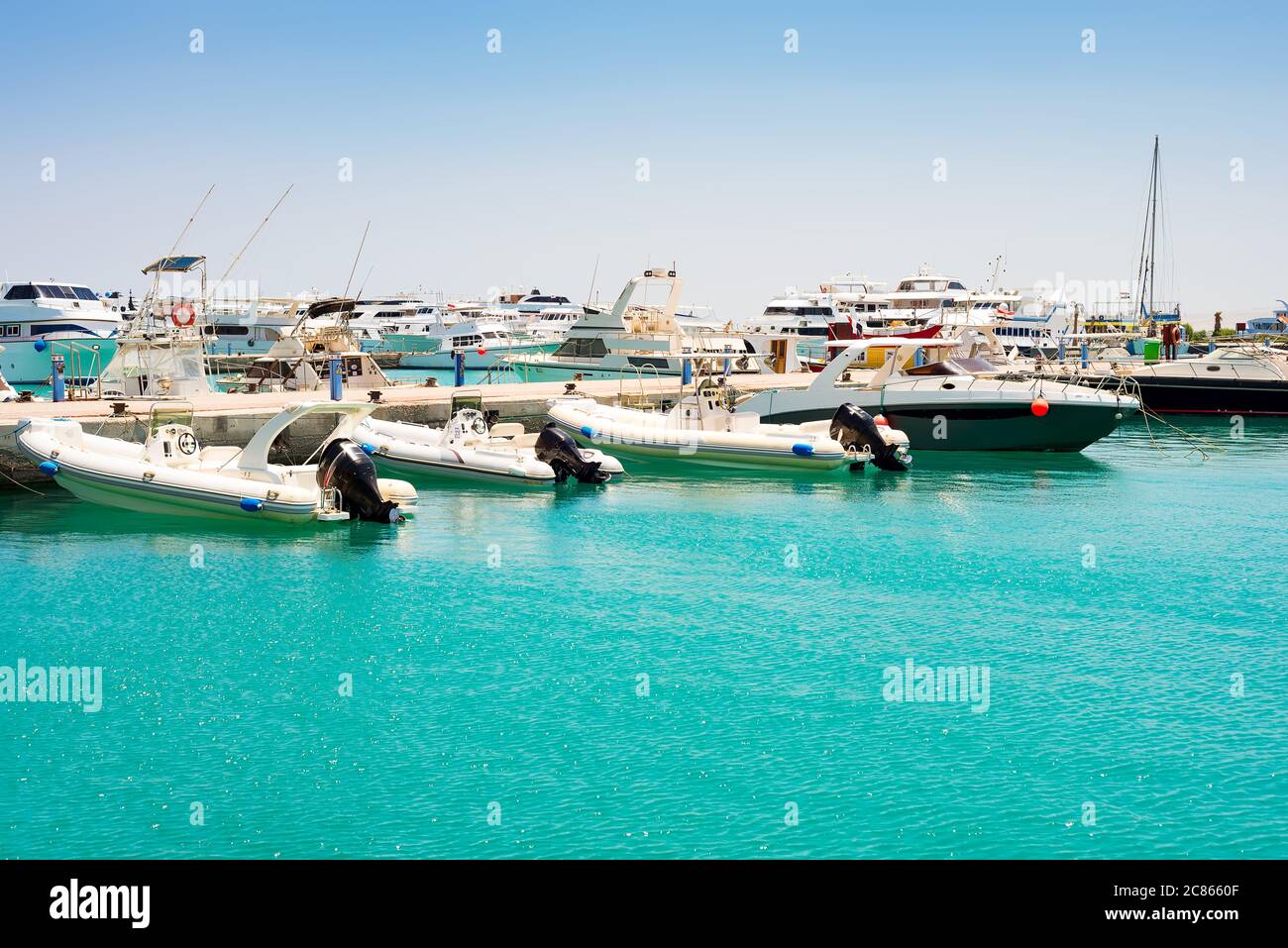 Modern high-speed boats and yachts parked near pierce on a turquoise ...