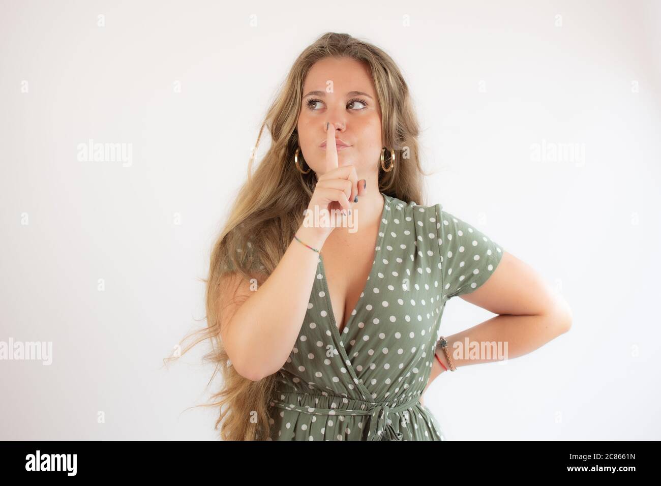 Pretty girl in green dress making silence gesture Stock Photo - Alamy