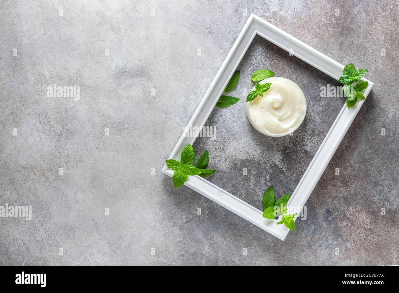 Composition of mint cosmetic products in a jar and green leaves of ...
