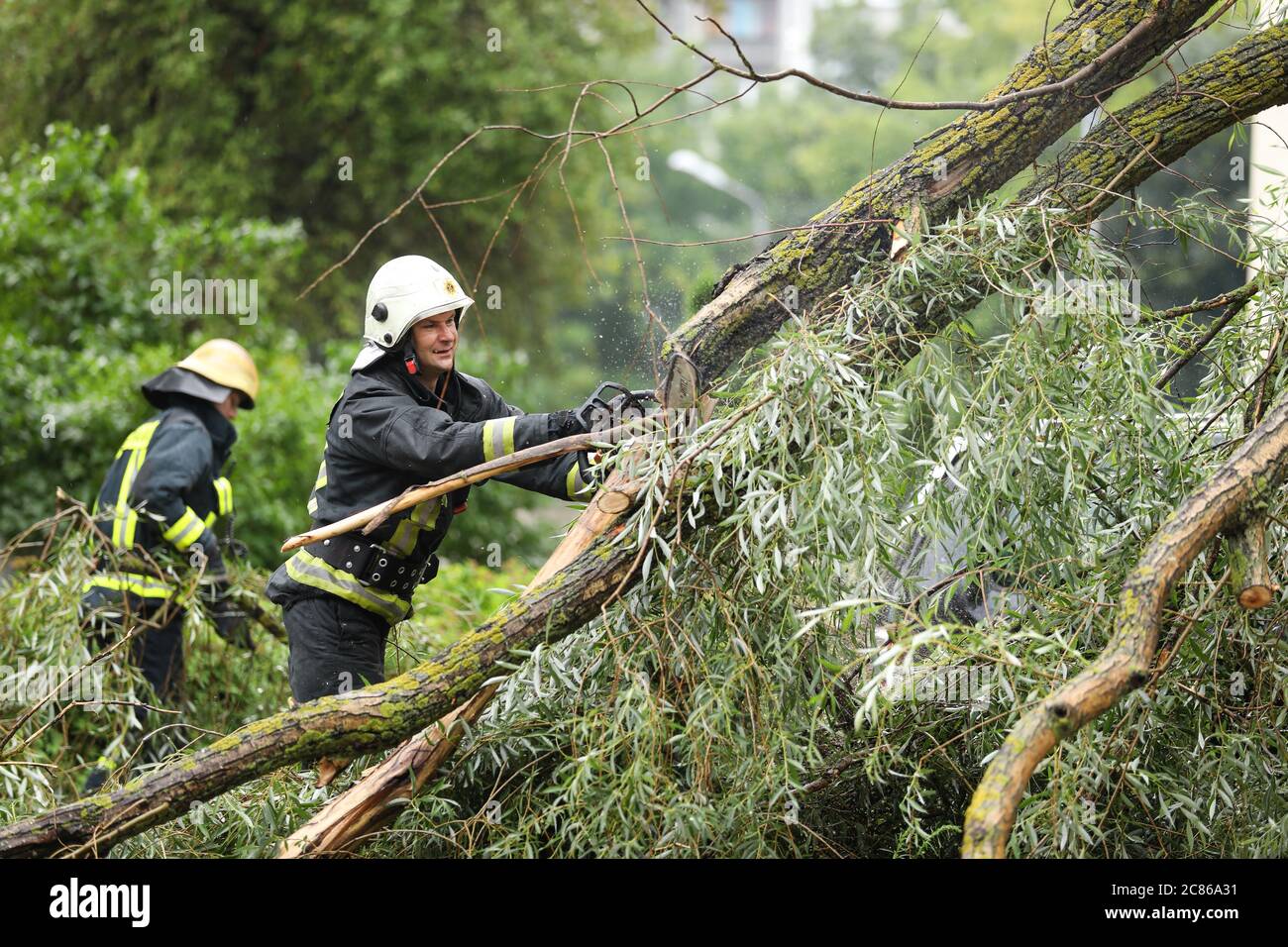 firefighters and police officer help clean up the effects of a fallen ...