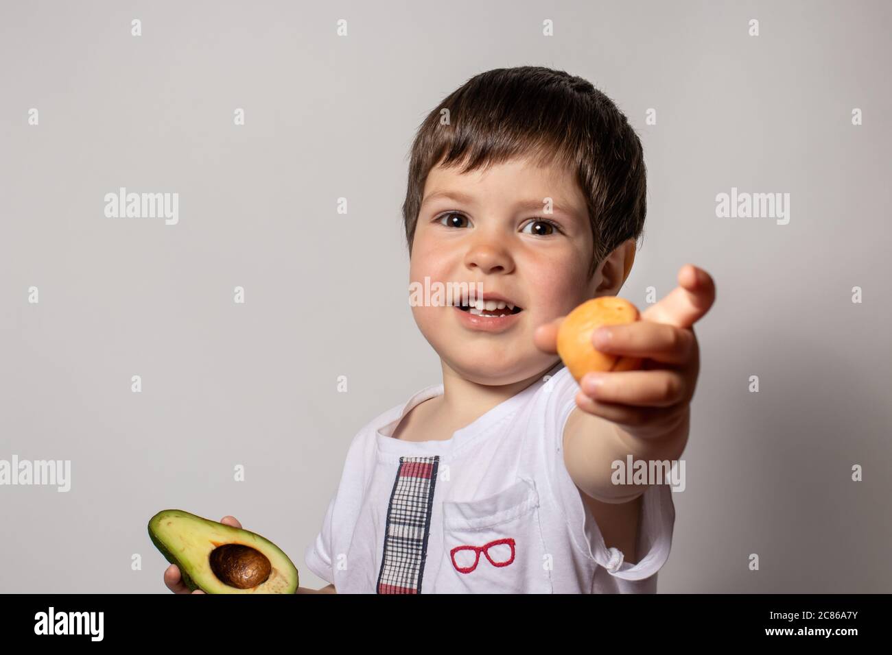 Little boy shares avocado. Proper nutrition of children. Green fruits ...