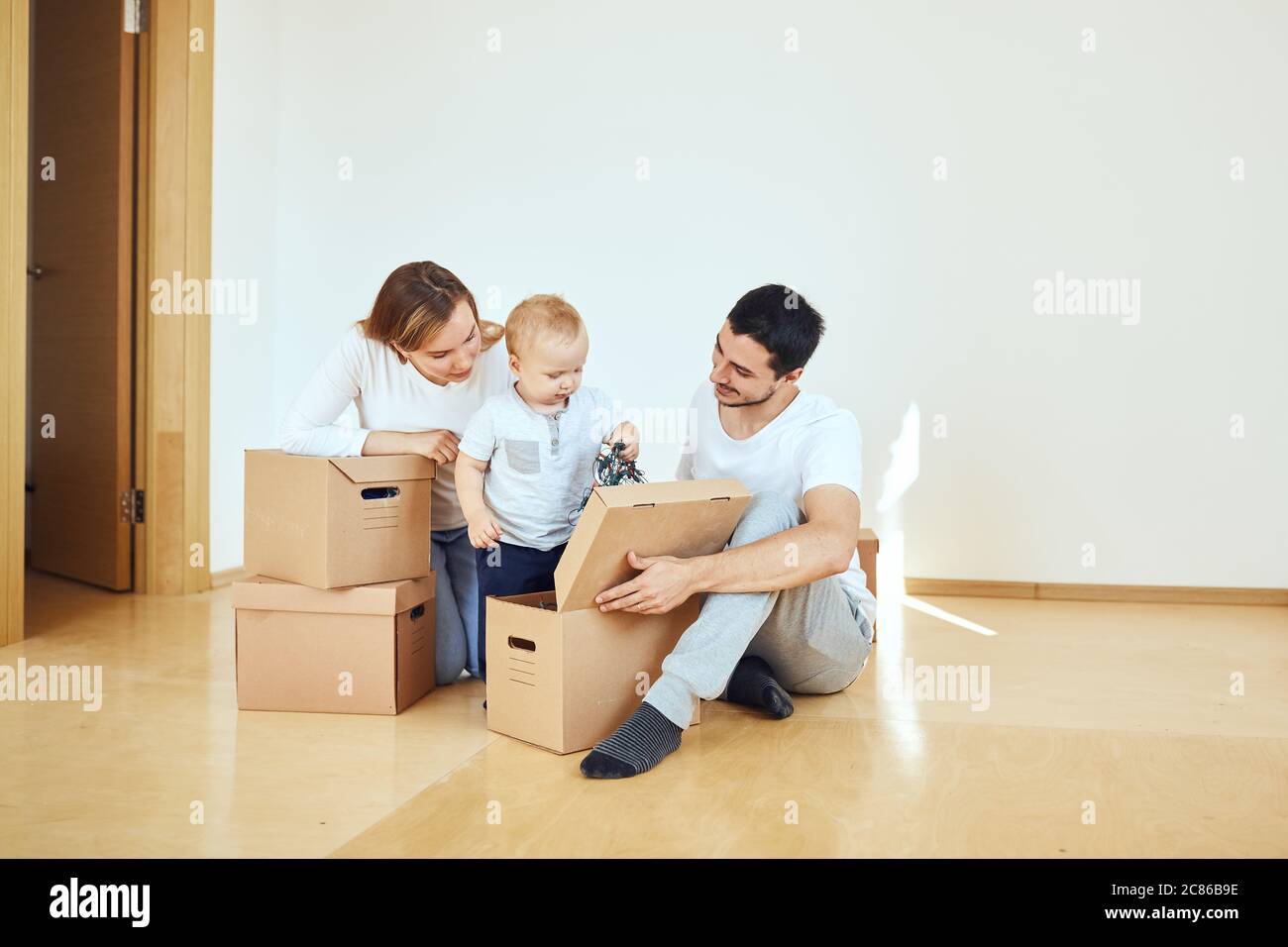 Family, parents and son, unpacking boxes and moving into new home, baby ...