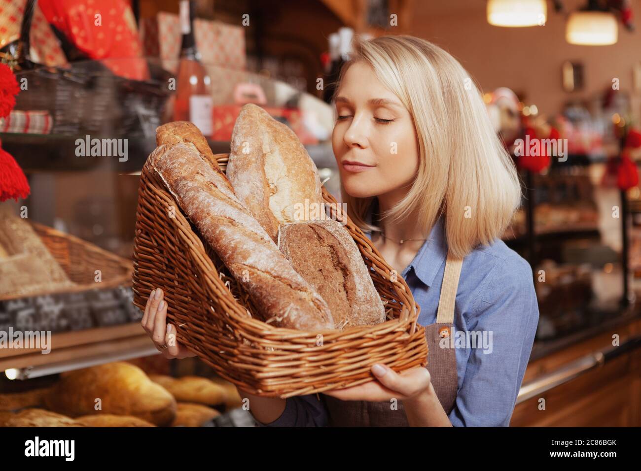 Beautiful female baker smelling fresh bread, enjoying working at her ...