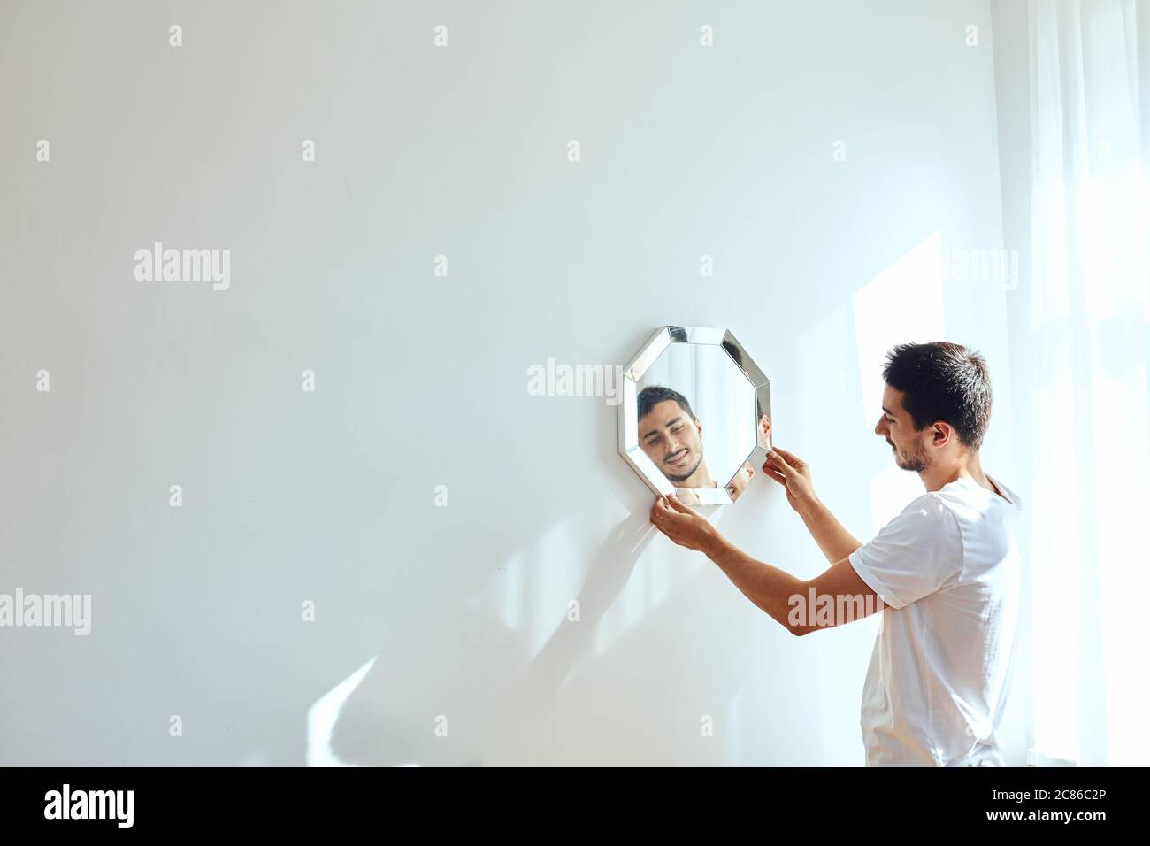 Studio portrait of young man standing near wall and hang mirror Stock ...