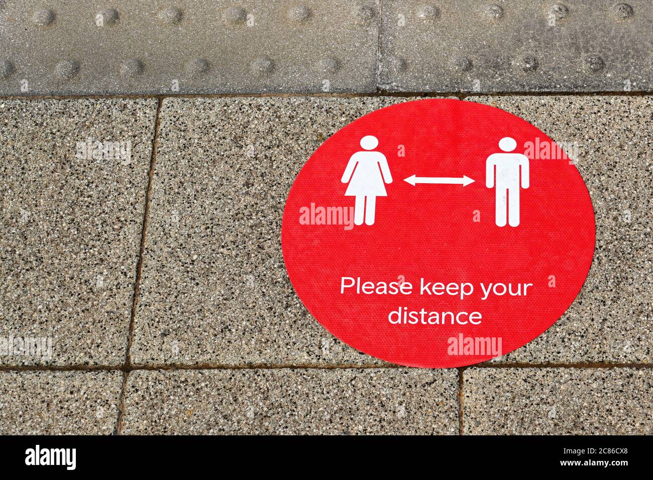 Circular red sticker on the ground asking people to maintain social ...