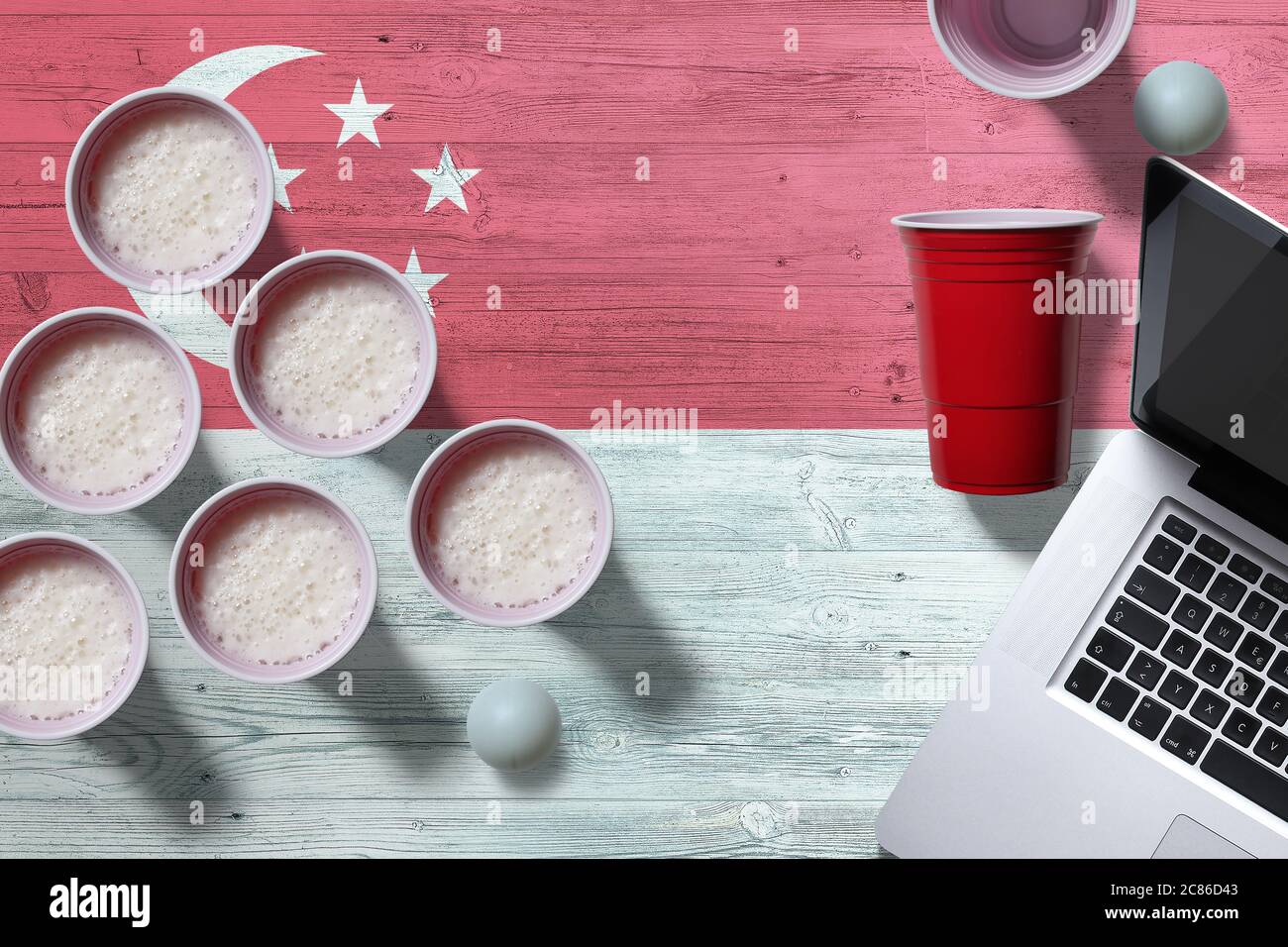 Singapore Flag Concept With Plastic Beer Pong Cups And Laptop On National Wooden Table Top View