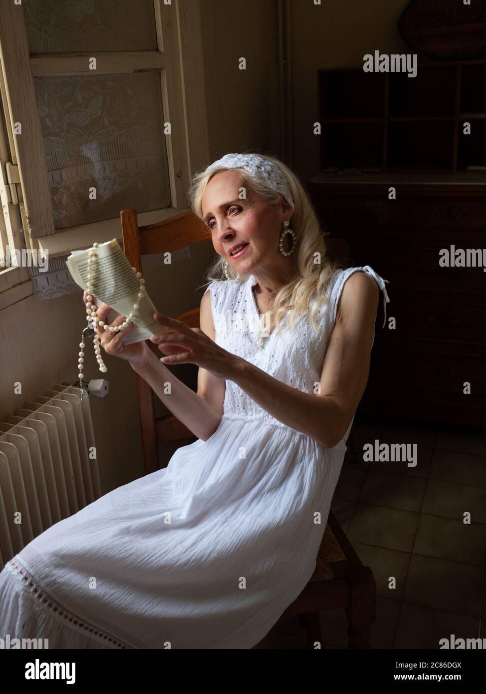Vertical portrait of a mature woman reading Scriptures with a rosary by ...