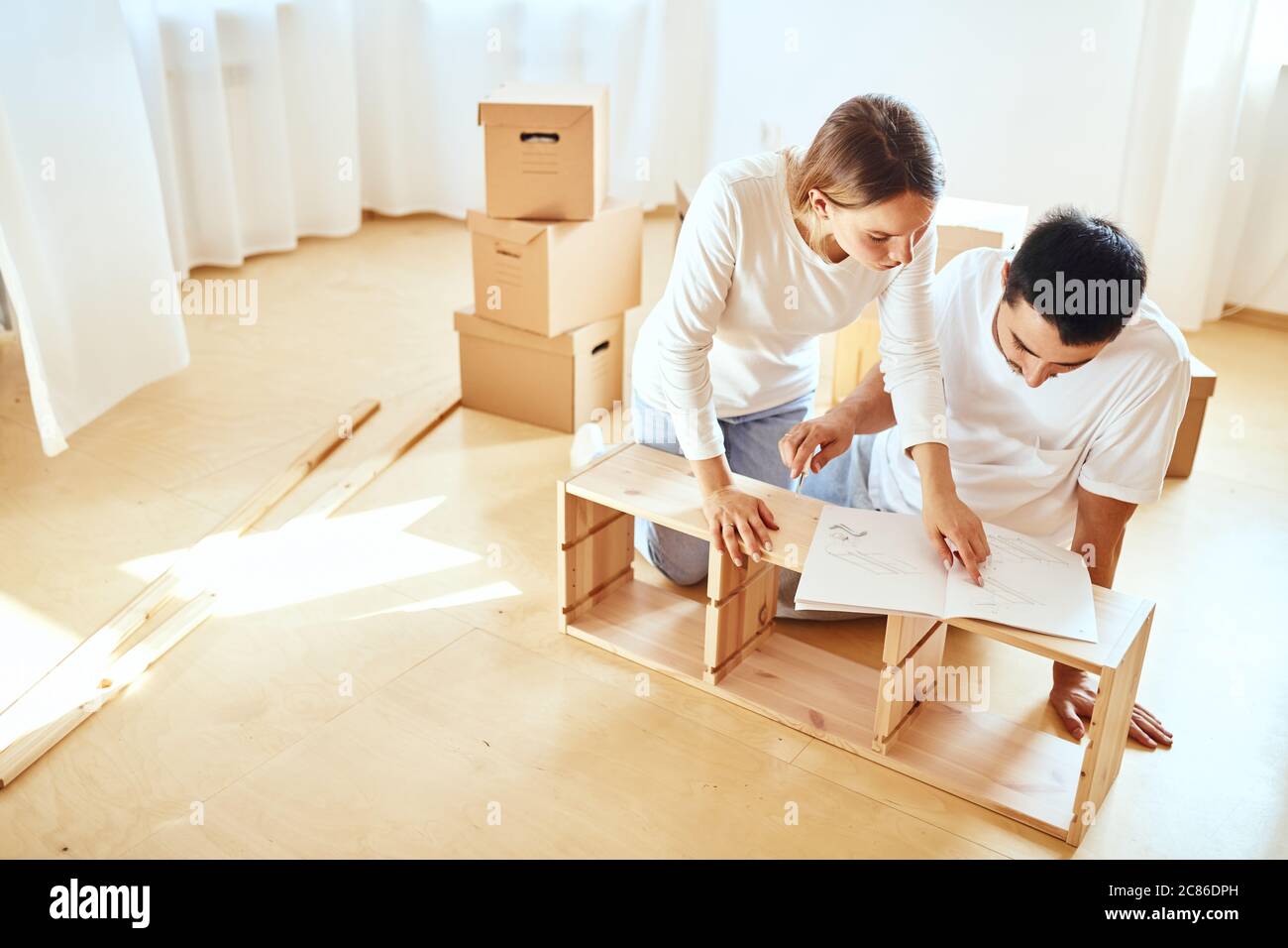 Young couple installing furniture in new house with instruction Stock ...
