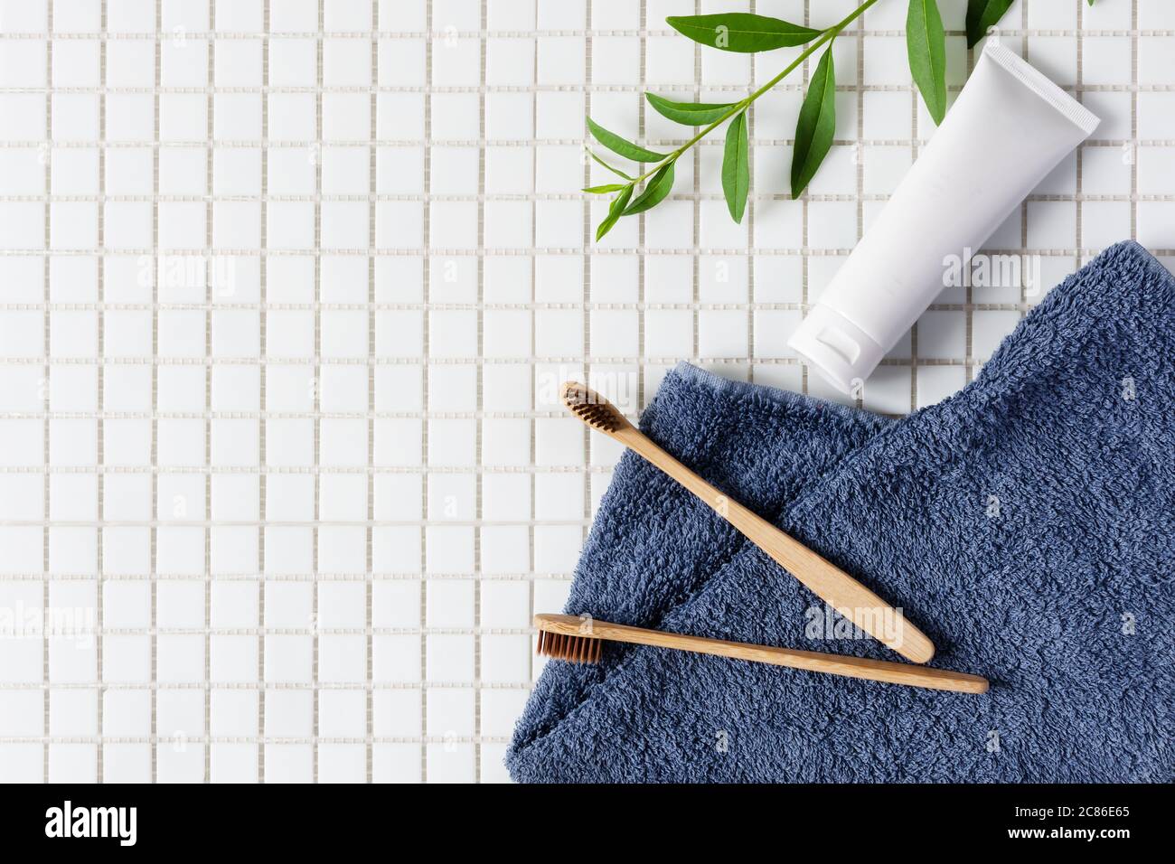 Bamboo toothbrush, toothpaste and towel on white mosaic background top ...