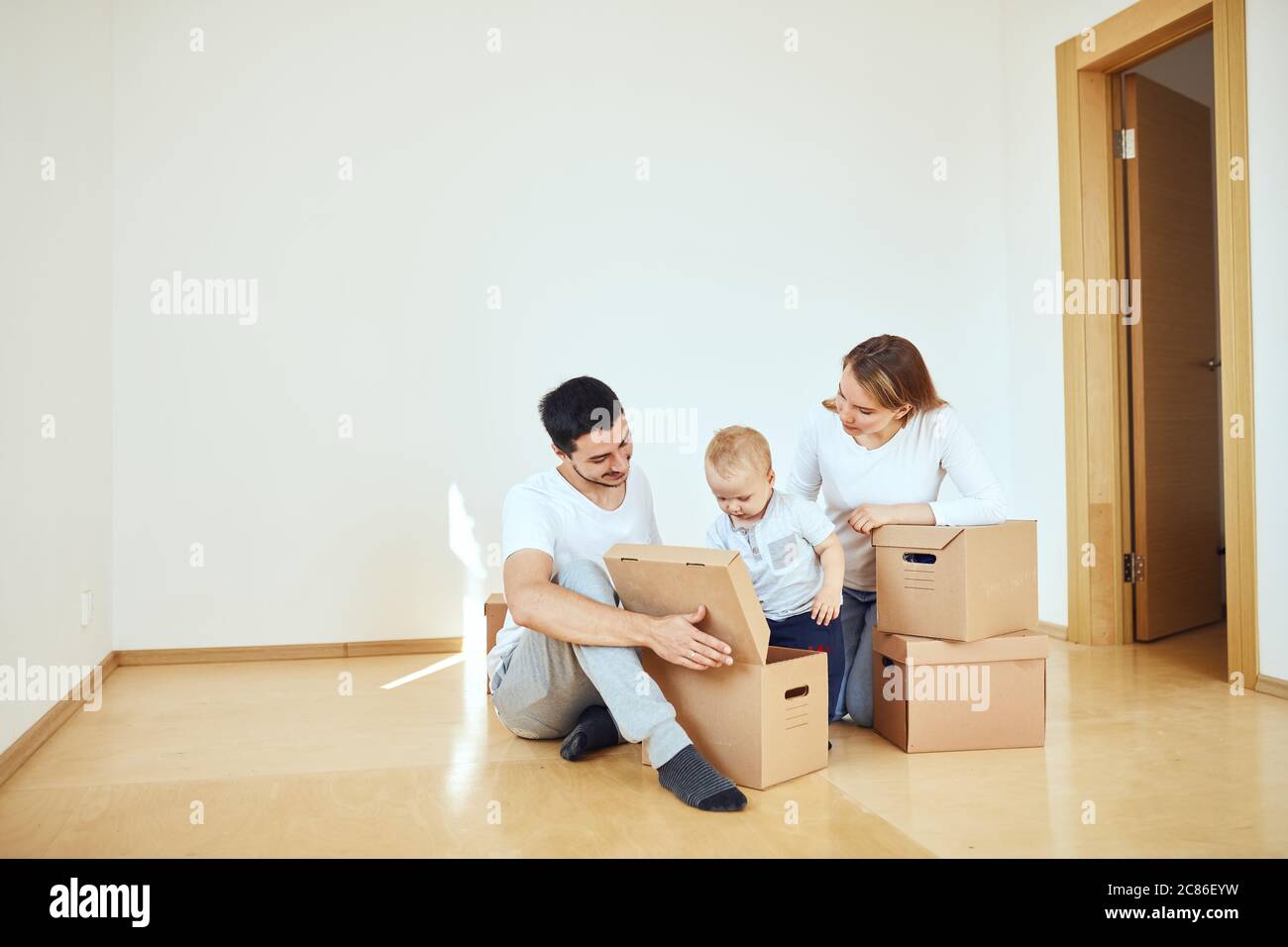 Family with little boy unpacking moving cardboard boxes at new home ...
