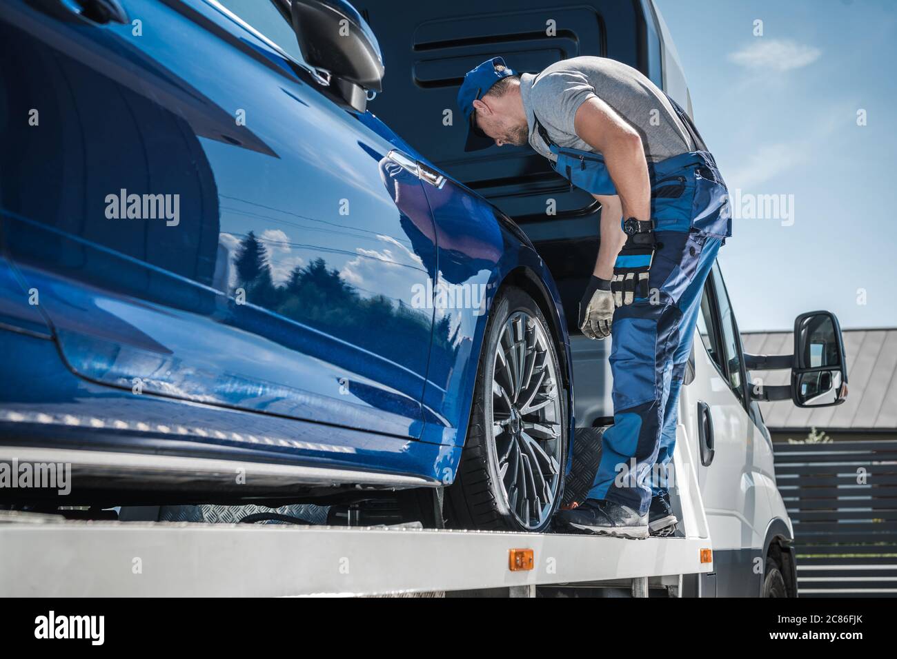 Car Repossession Worker Securing Vehicle on His Towing Truck. Vehicle ...