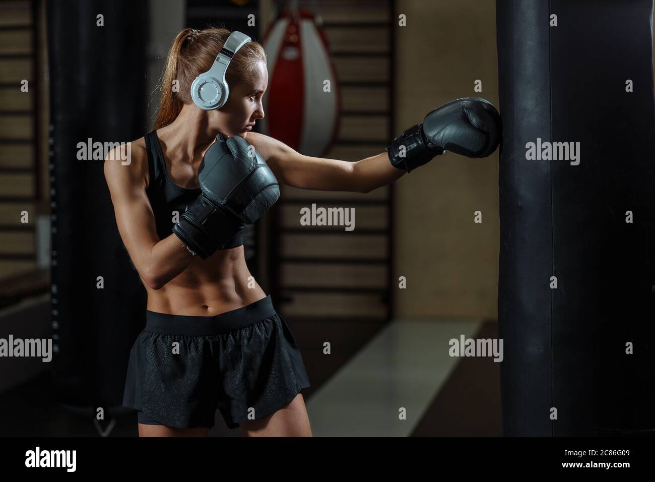 blond woman with boxing gloves, standing in position, ready to fight ...