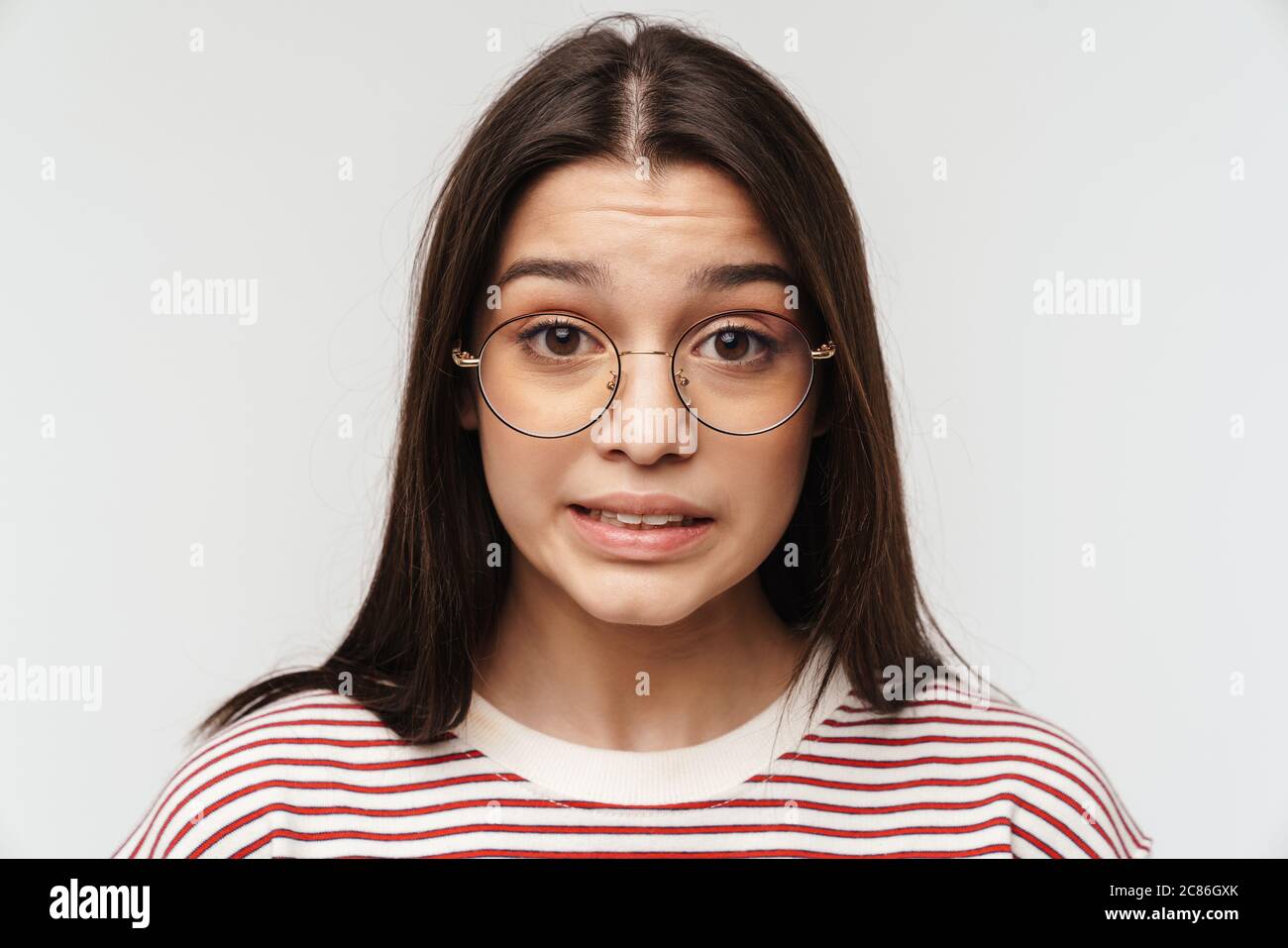 Portrait of a pretty confused young brunette woman wearing casual ...