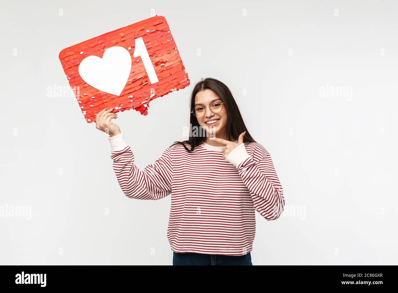 Photo of happy brunette young woman smiling and holding like symbol ...