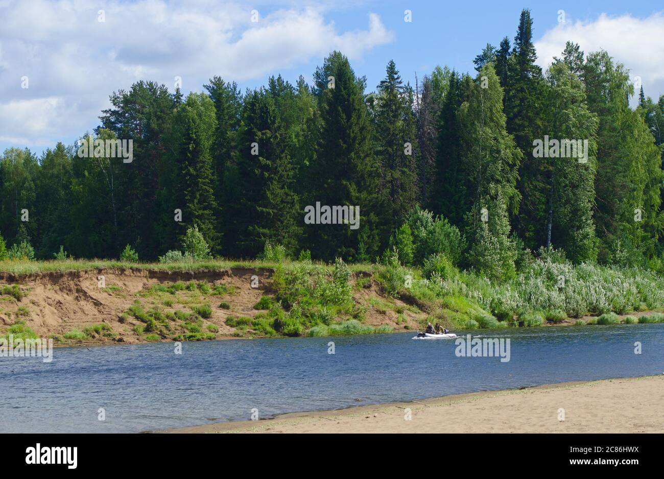 landscape shot of a river with a steep Bank and a motor boat going up ...