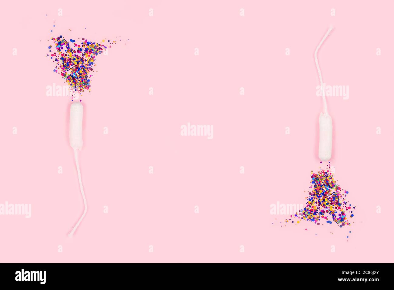 Two clean cotton tampons with colorful sparkles on pink background with ...