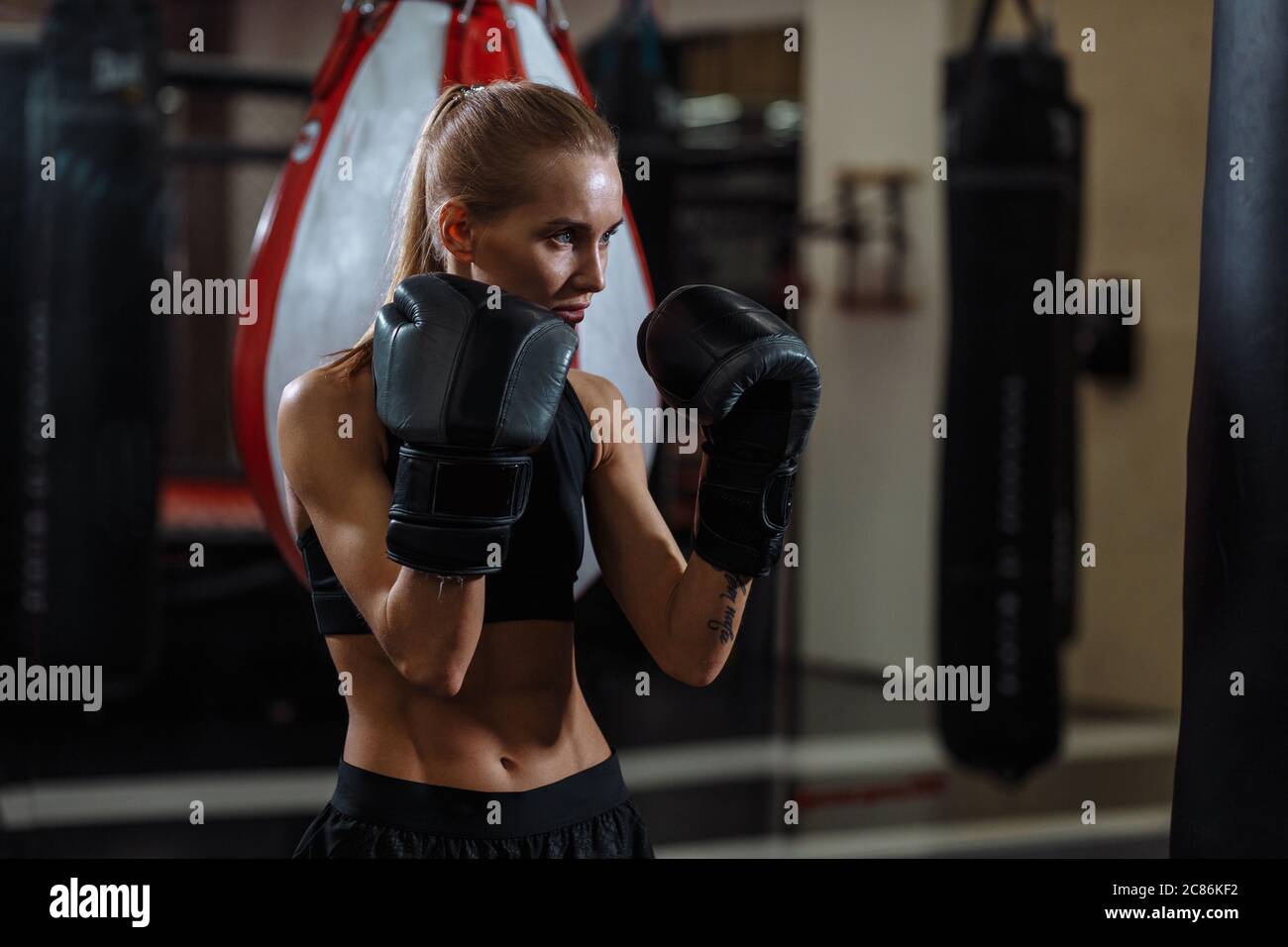 young female boxer in gloves standing in defense pose and looking ...