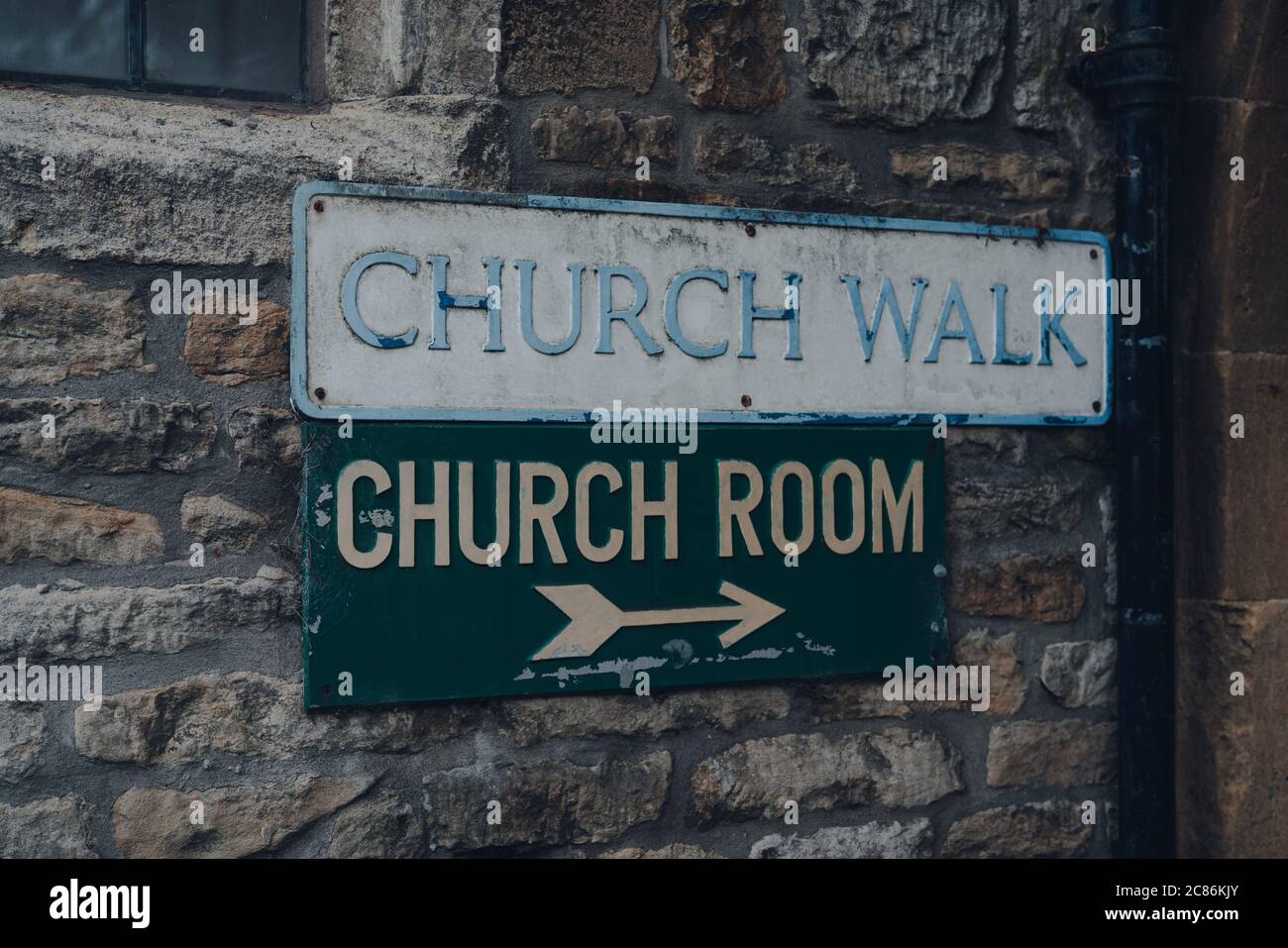 Street name sign and a directional arrow to church room on a limestone ...