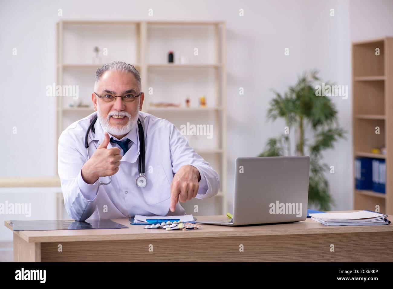 Old experienced doctor working in the clinic Stock Photo - Alamy