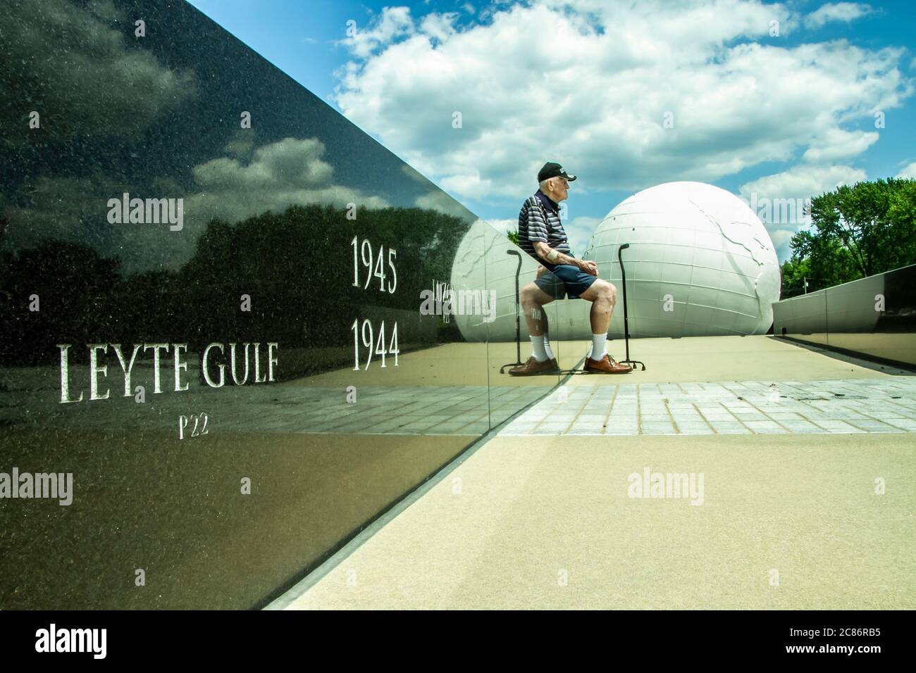 WWII US Navy veteran sits on wall of WWII monument Stock Photo - Alamy