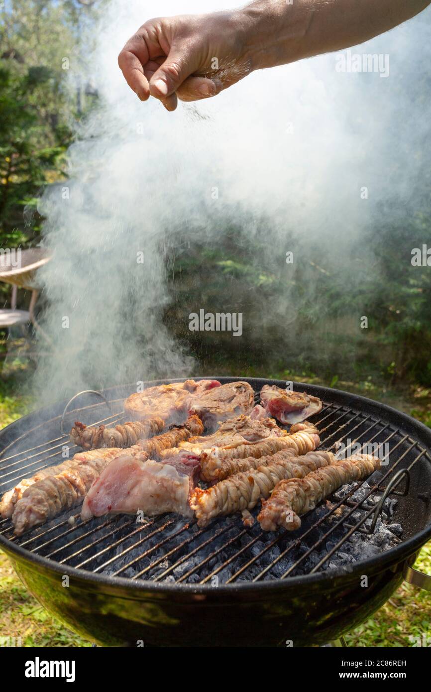 Seasoning being sprinkled over meat cooking on a coal barbecue in Zakynthos Greece Stock Photo Alamy