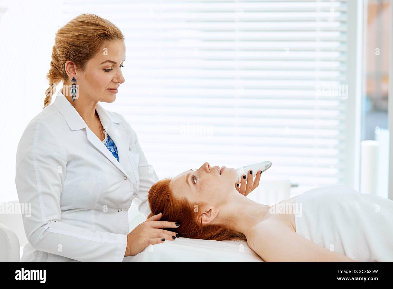 Skilled professional mature female beautician in white uniform ...