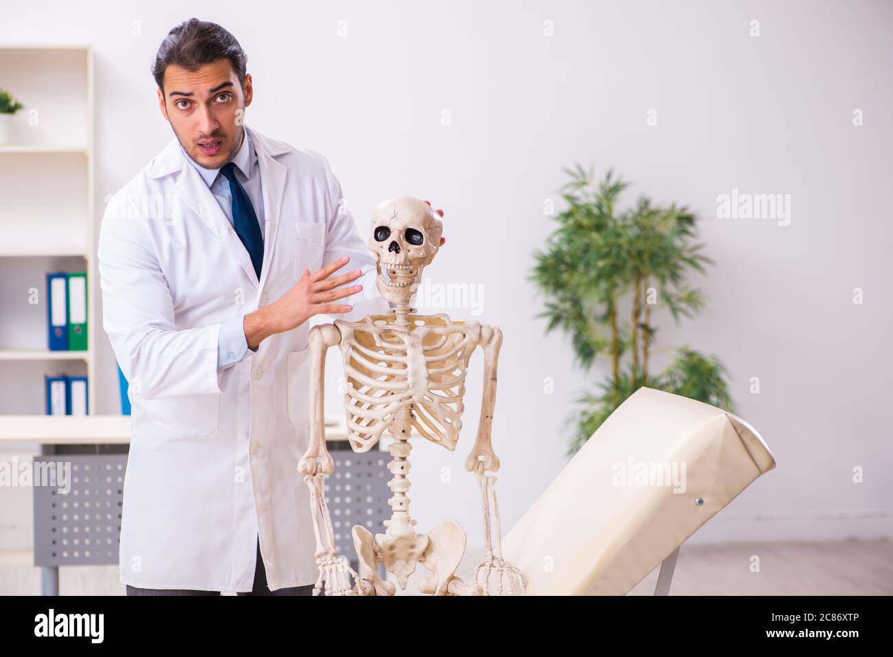 Young male doctor with the skeleton Stock Photo - Alamy