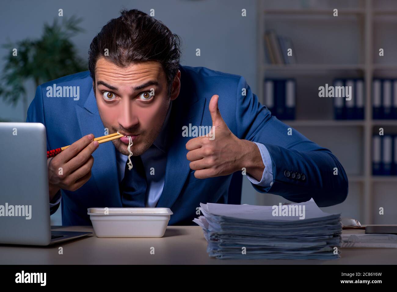 Hungry employee working late in office Stock Photo - Alamy