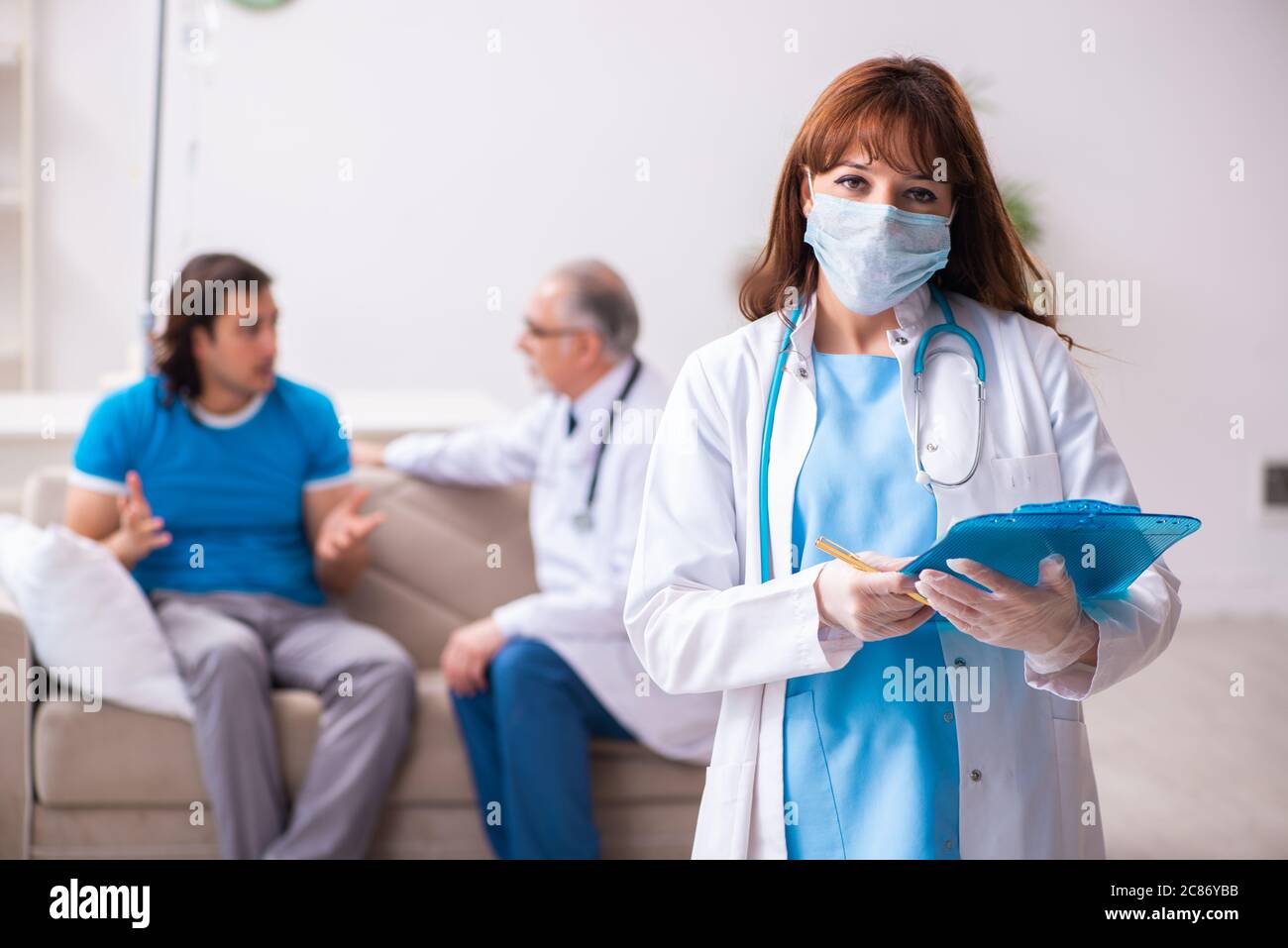 Two doctors visiting sick man at home Stock Photo - Alamy