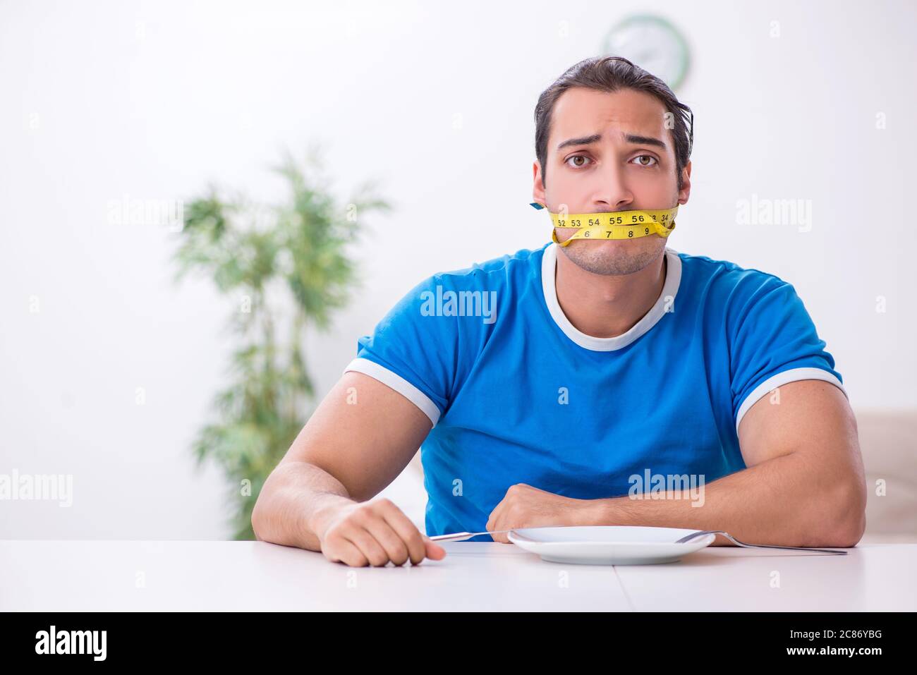 Young hungry man in the dieting concept Stock Photo - Alamy