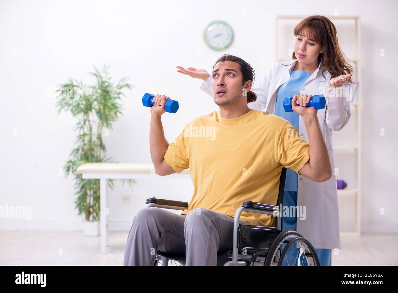 Young male patient in wheel-chair doing physical exercises in hospital ...