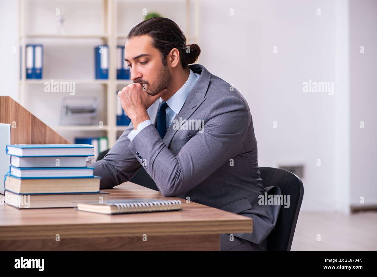 Young businessman reading books at workplace Stock Photo - Alamy