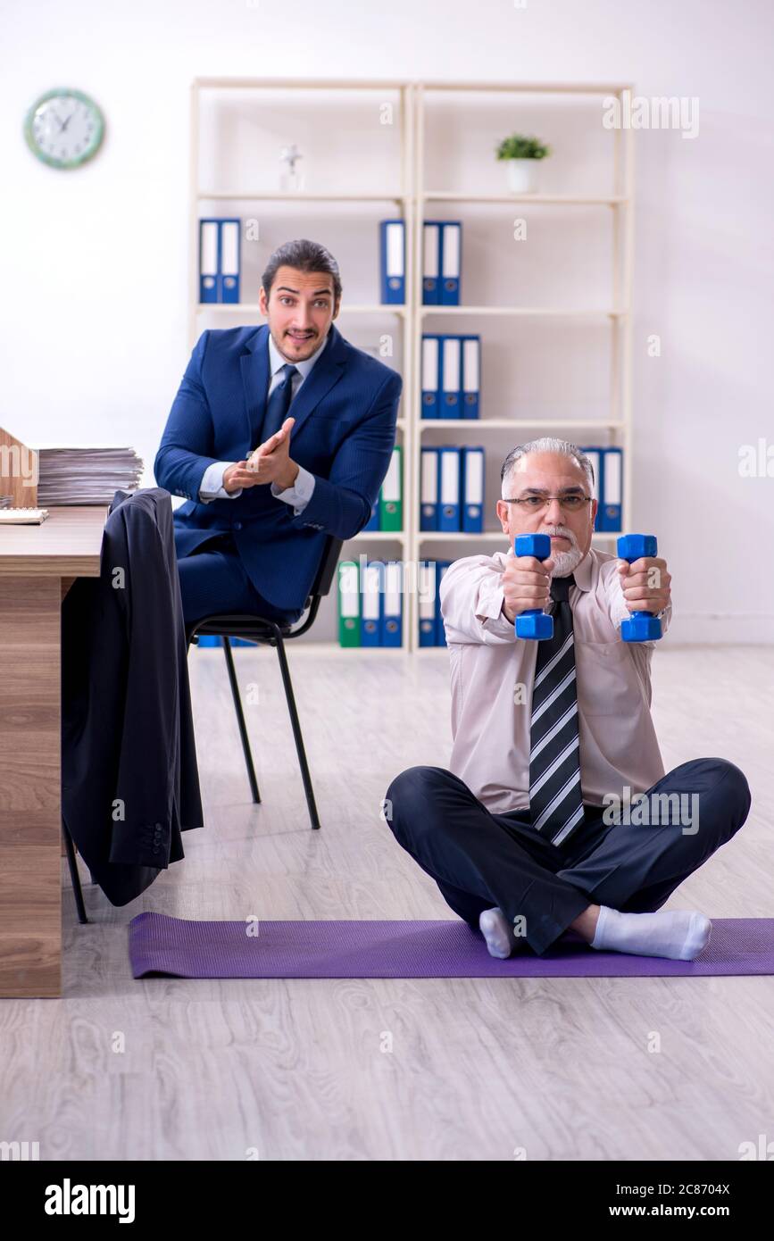 Two employees doing physical exercises at the workplace Stock Photo - Alamy