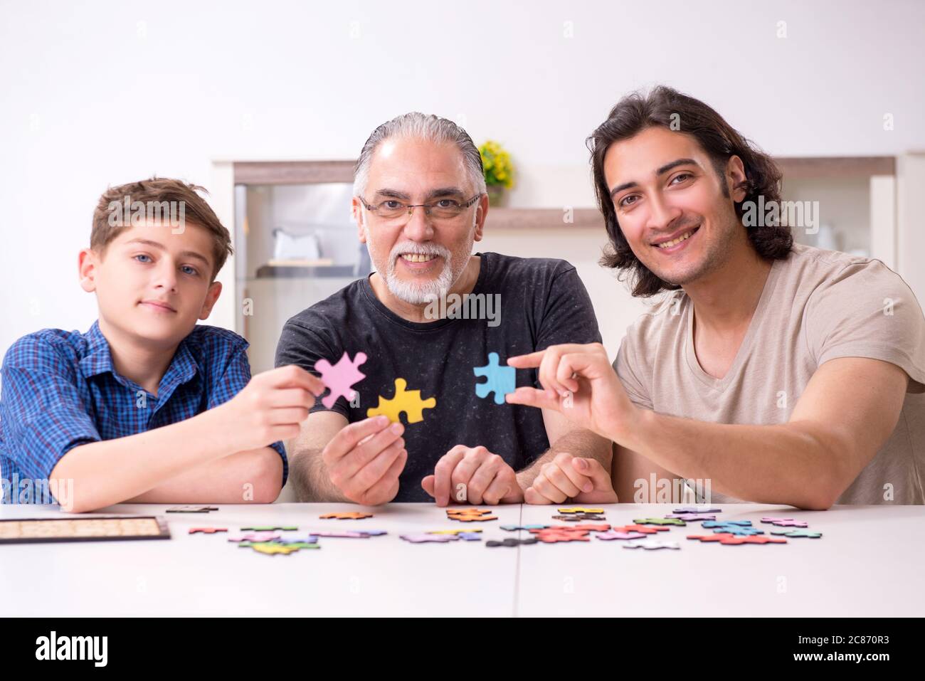 Three generations of family playing jigsaw puzzle Stock Photo - Alamy