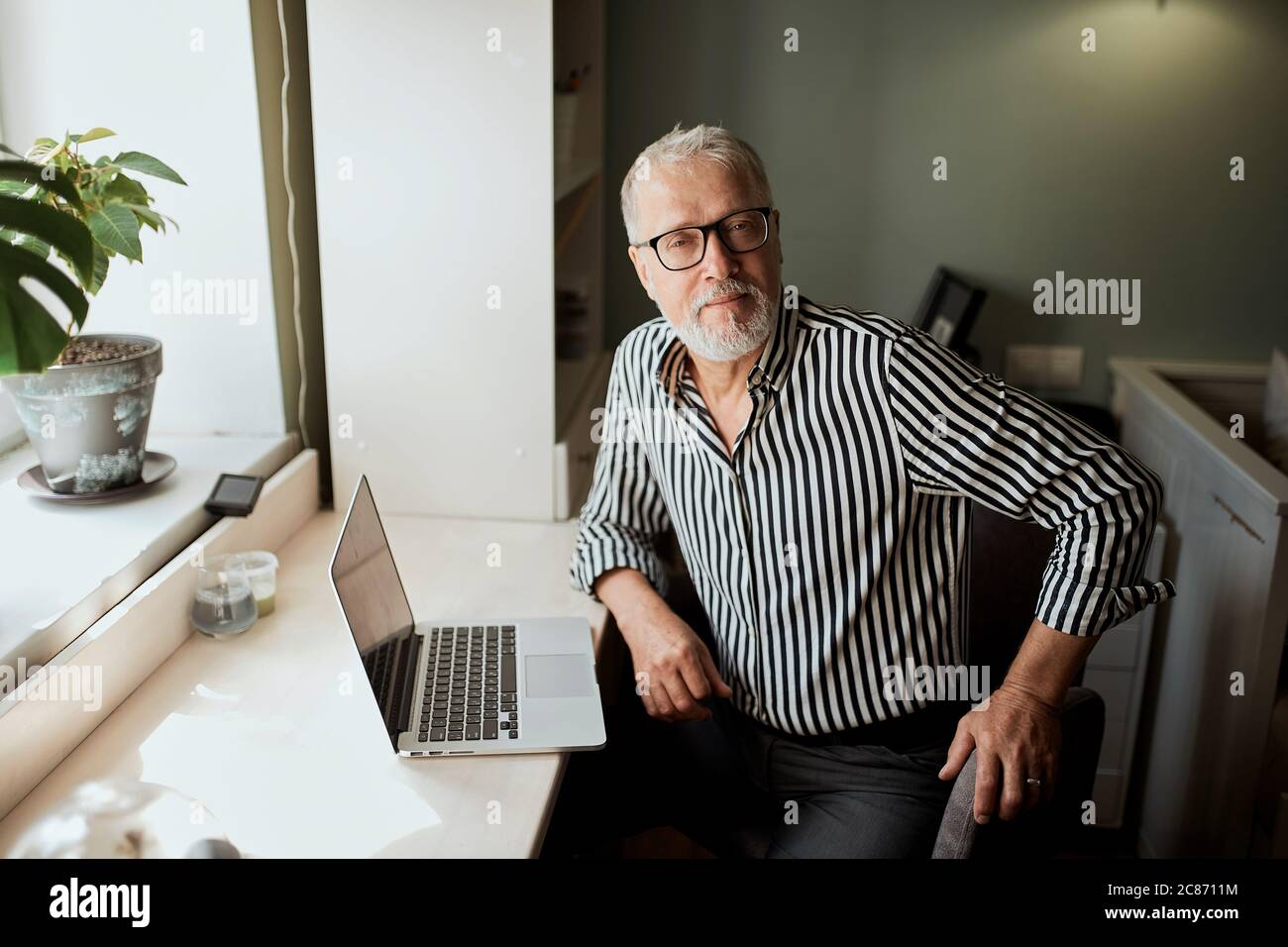 Trendy mature bearded man working from home with laptop. sitting at ...
