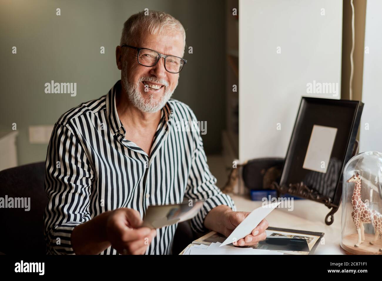 Senior man looking old photographs in home. Reminisce about past Stock ...