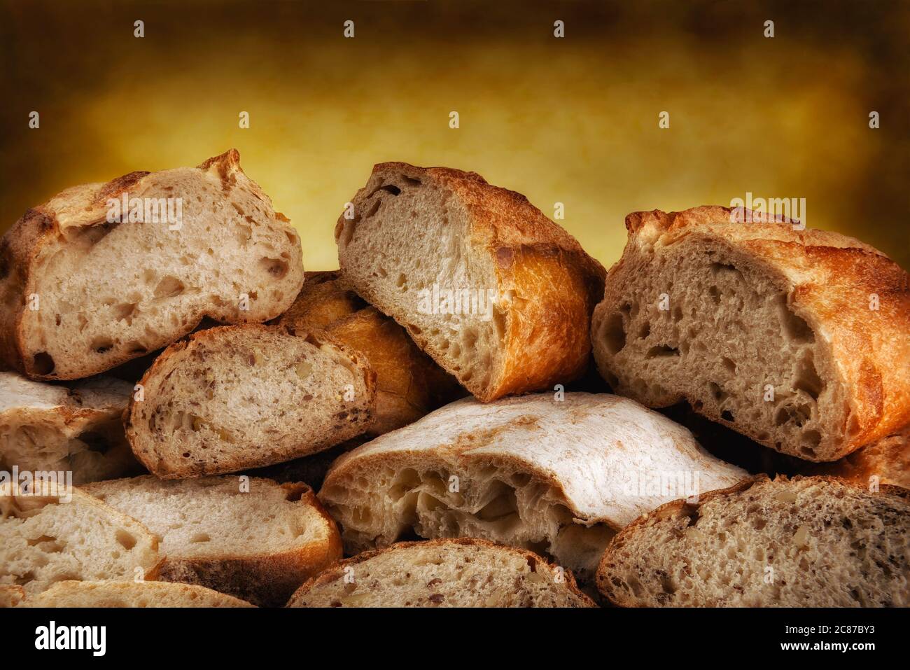 A variety of fresh baked bread on a warm background, the loaves are cut ...