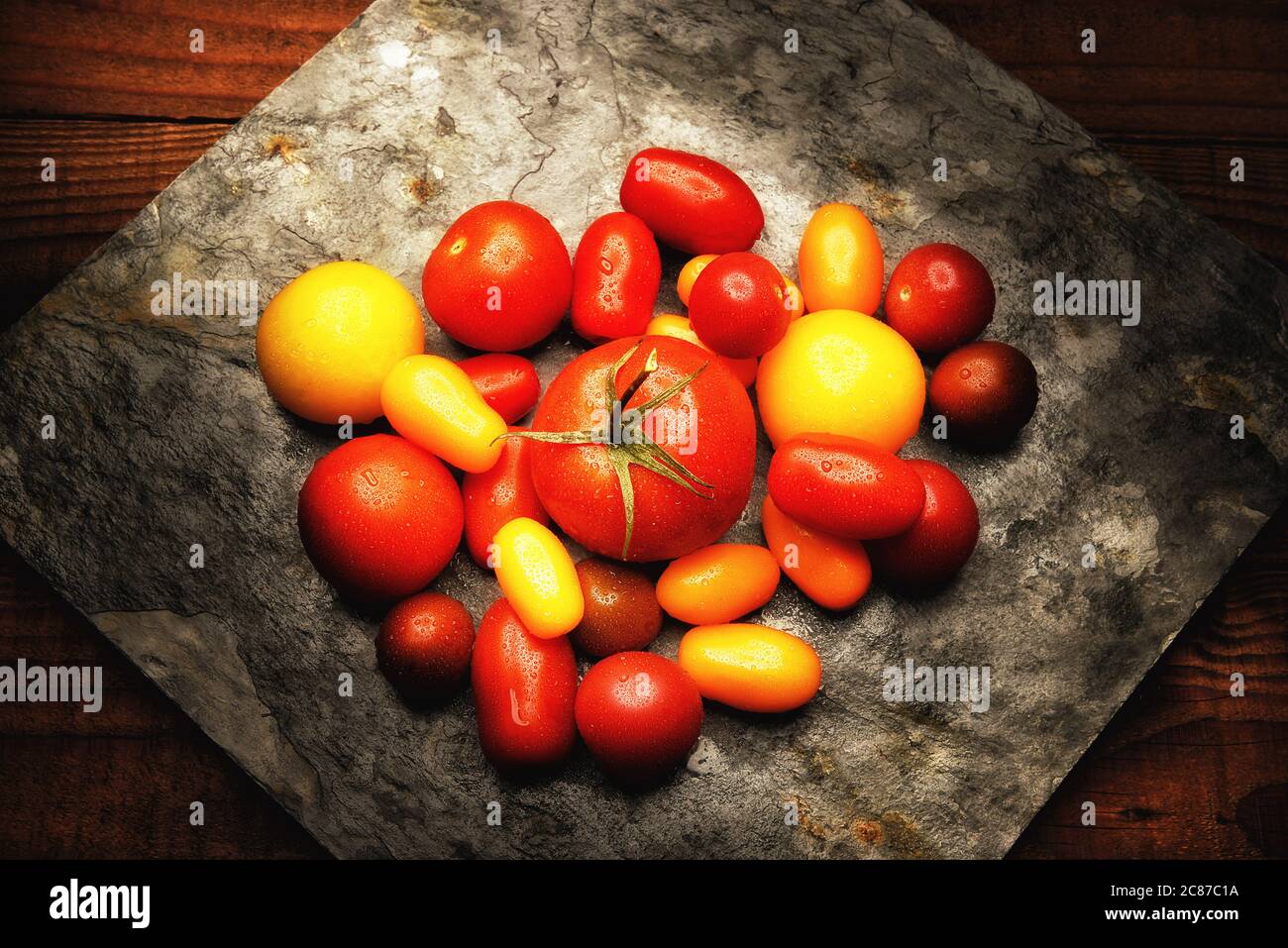 Flat lay still life of a group of Medley Tomatoes on a slab of slate on ...
