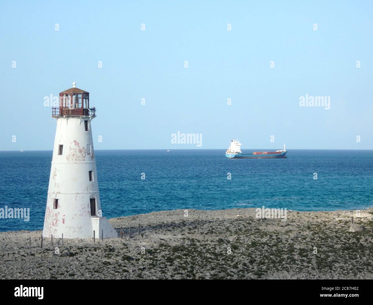 Small white lighthouse at Nassau Bahamas with commercial ship in ...