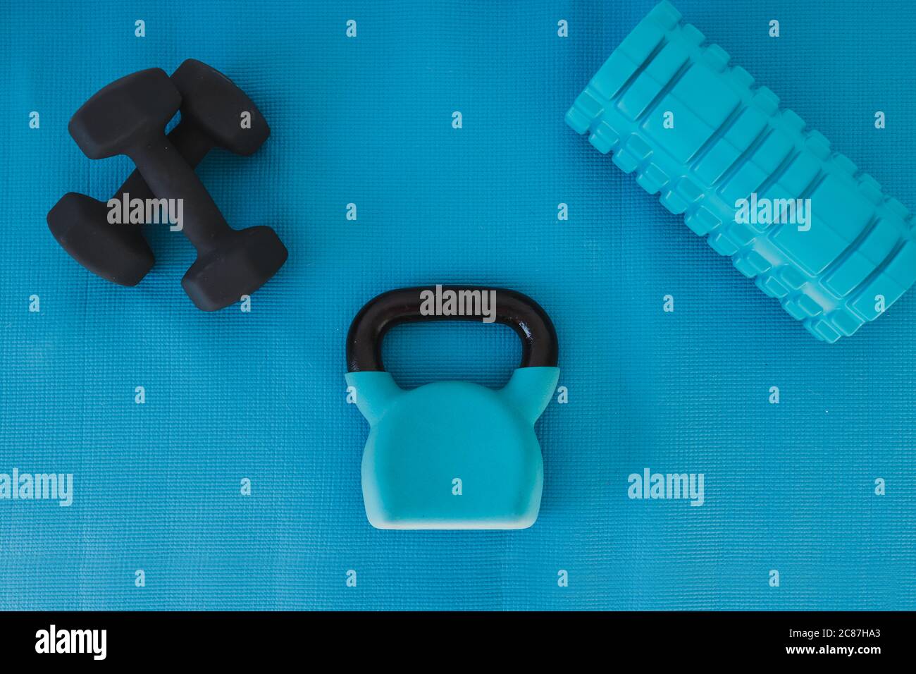 home gym concept, blue yoga mat with kettlebell foam roller and ...