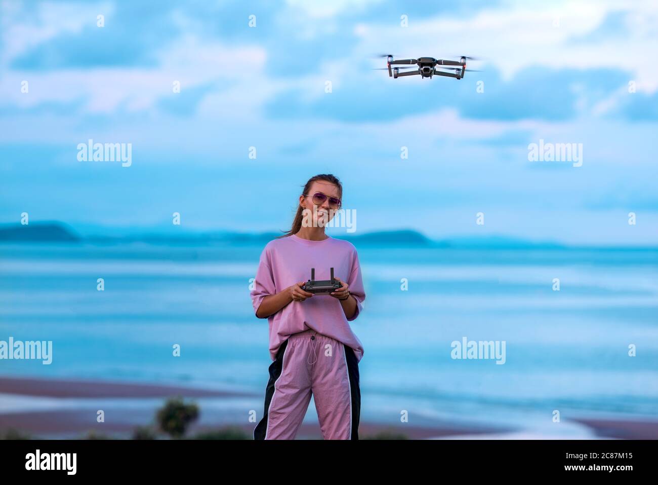 Cute lady in pink stylish clothes controls the drone with remote ...