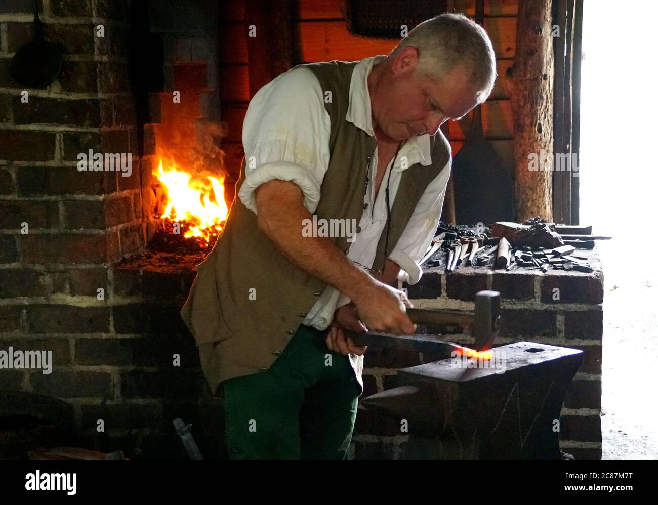 Williamsburg, Virginia, U.S.A - June 30, 2020 - A man shaping a molten ...