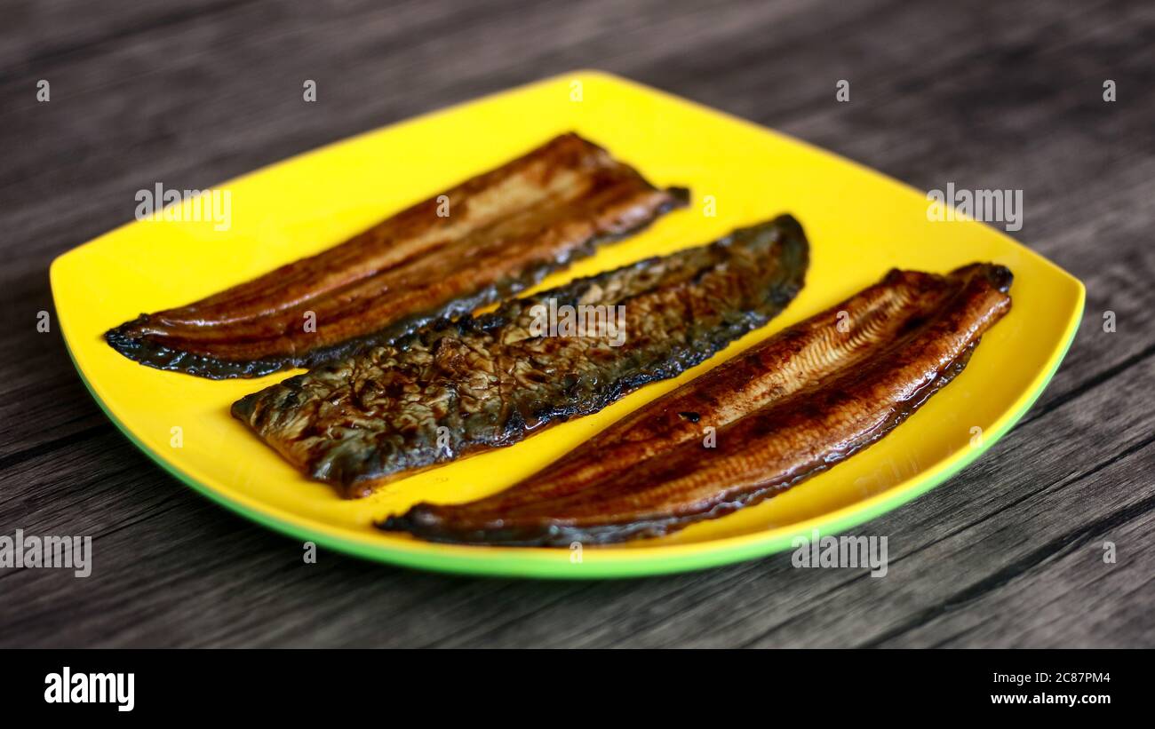 Eel fish or unagi on yellow plate on wood background. Ready to cook ...