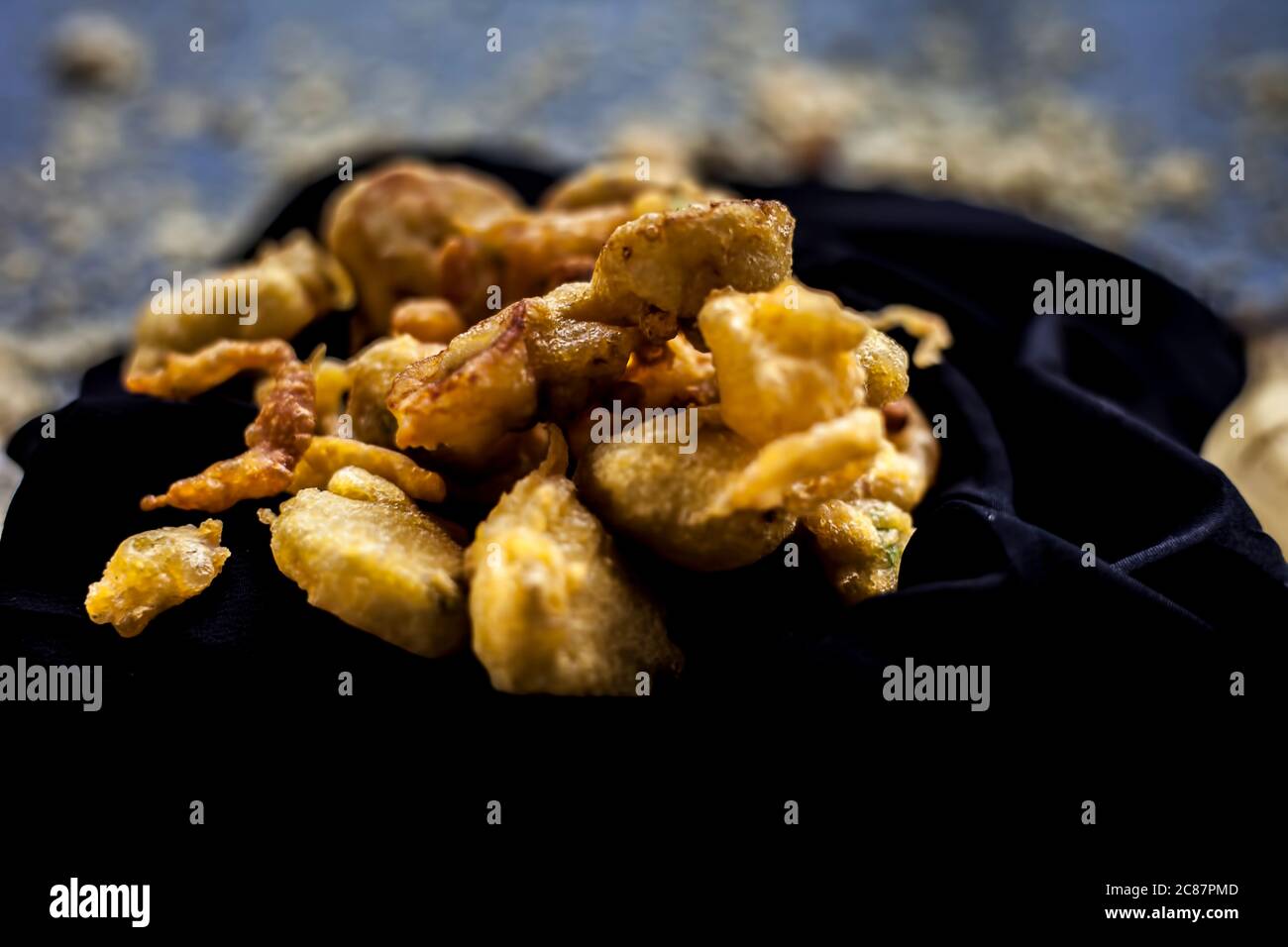 The famous shot of banana bhajia in a black colored container along ...