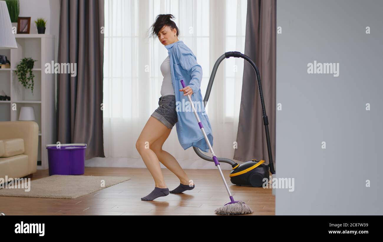 Happy woman dancing while cleaning the floor house with mop Stock Photo ...