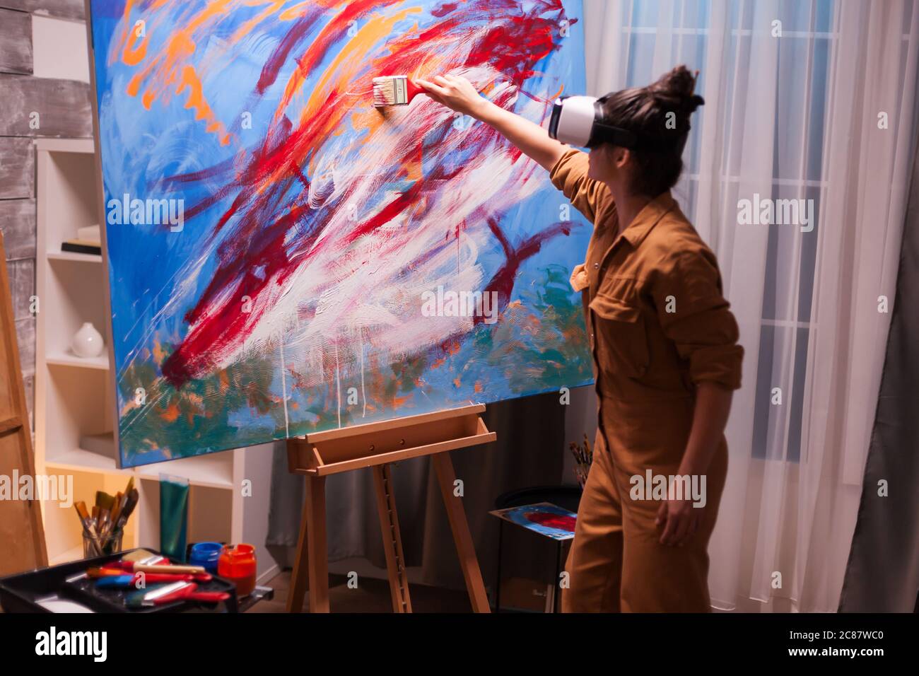 Artist wearing vr headset and painting in art studio. Modern artwork ...